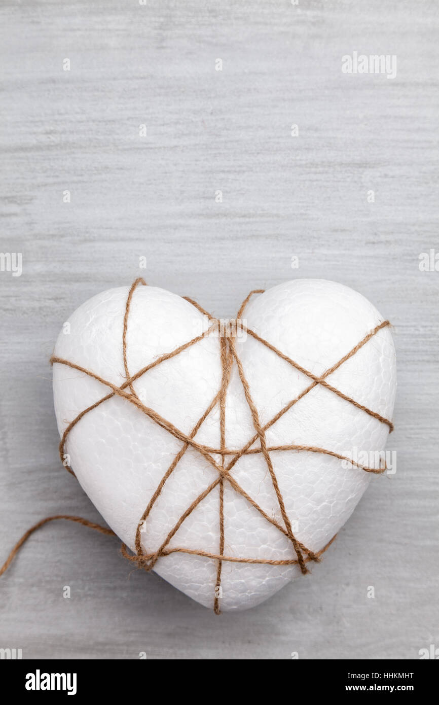 Heart bound by a string on grey rustic background Stock Photo - Alamy