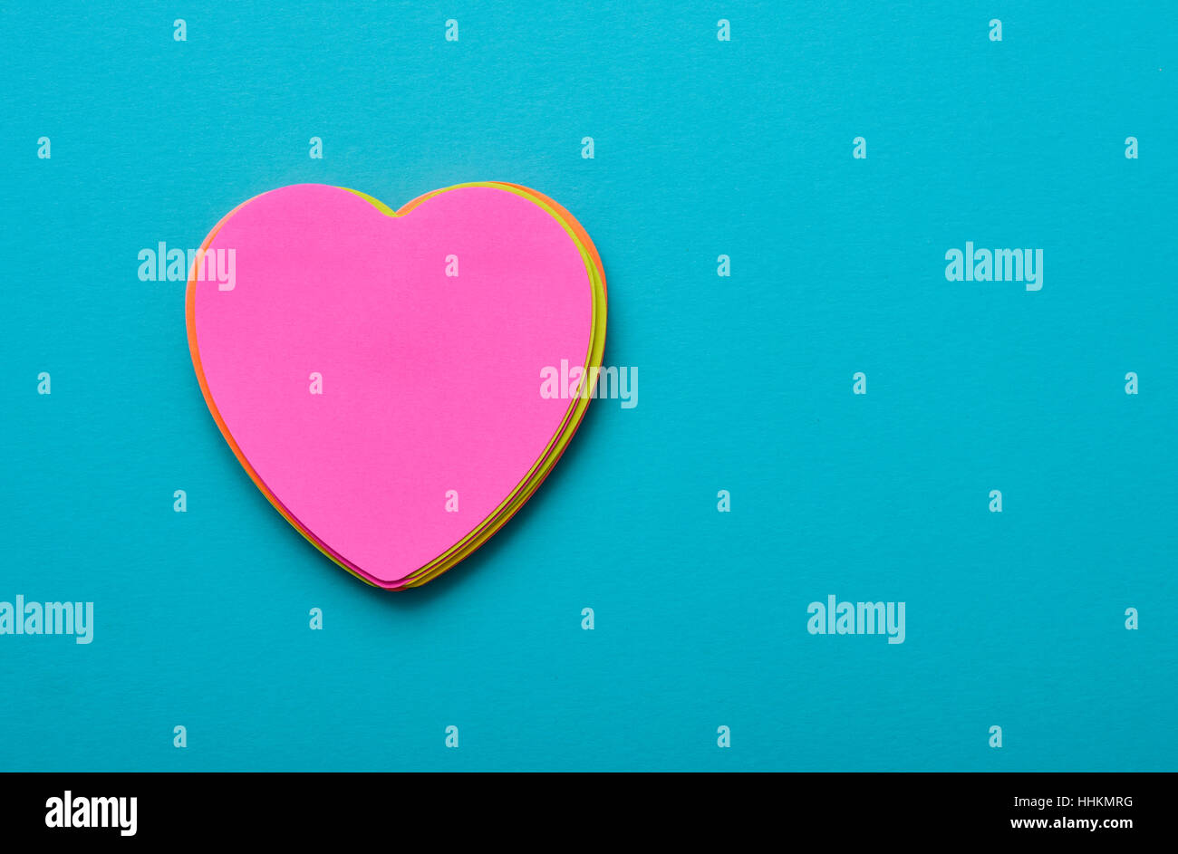 a stack of heart-shaped sticky notes of different colors topped by a ...