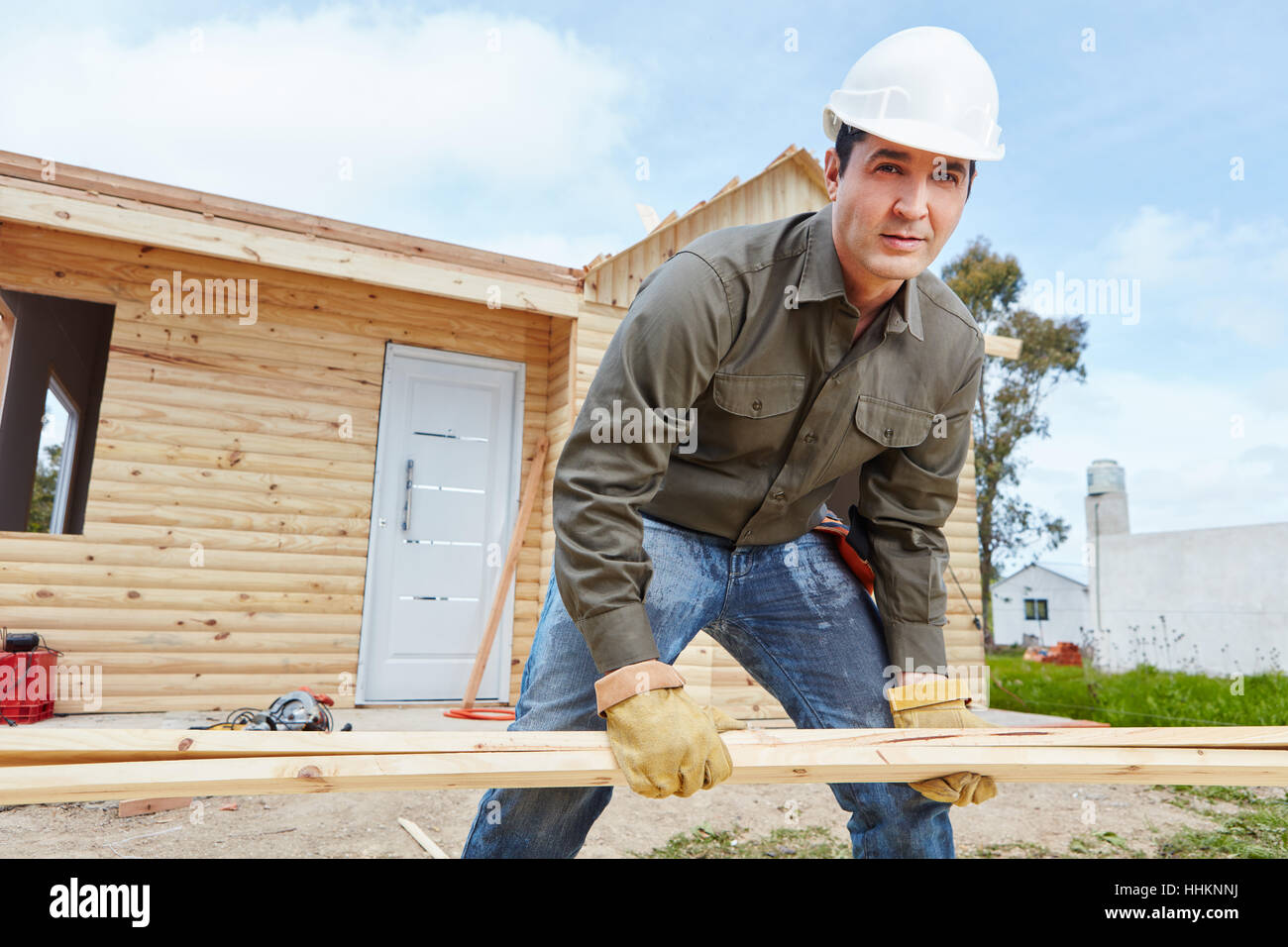 Man as handyman at construction site building woodhouse Stock Photo - Alamy