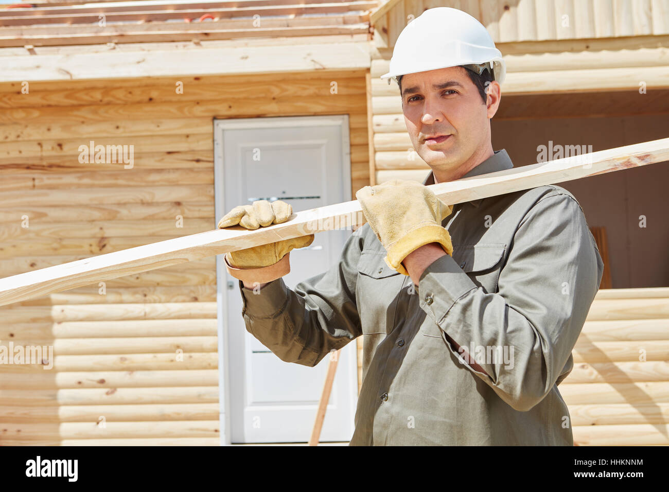 Worker carrying wood at construction site during building construction ...