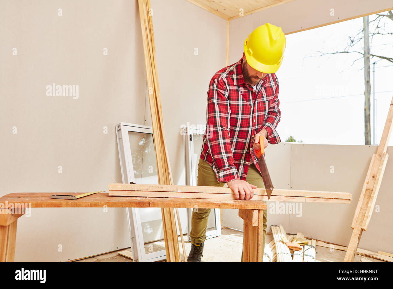 Carpenter cutting wood with saw at building Stock Photo - Alamy