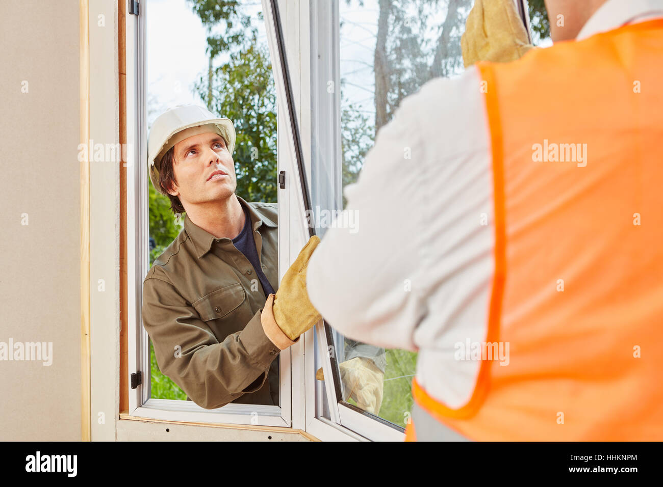 Two men installing window mount at construction site Stock Photo - Alamy