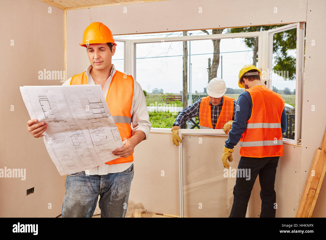 Window fitter team with floorplan modernizing new house Stock Photo - Alamy