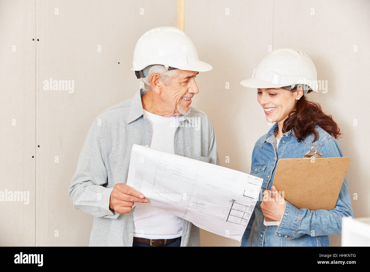 Architect with architectural drawing and apprentice planning building ...