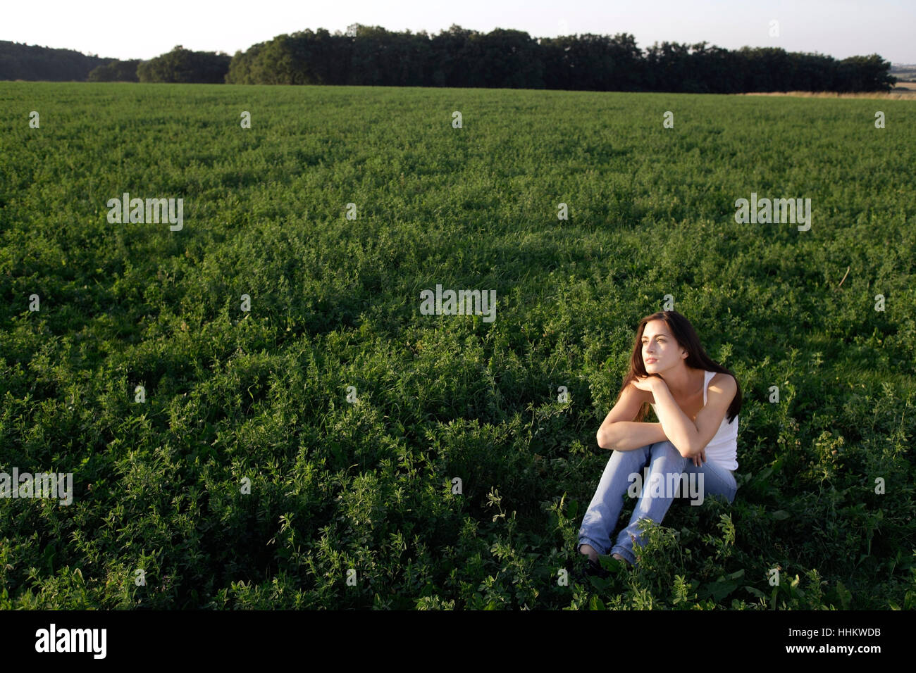 Young woman sitting in field Stock Photo - Alamy