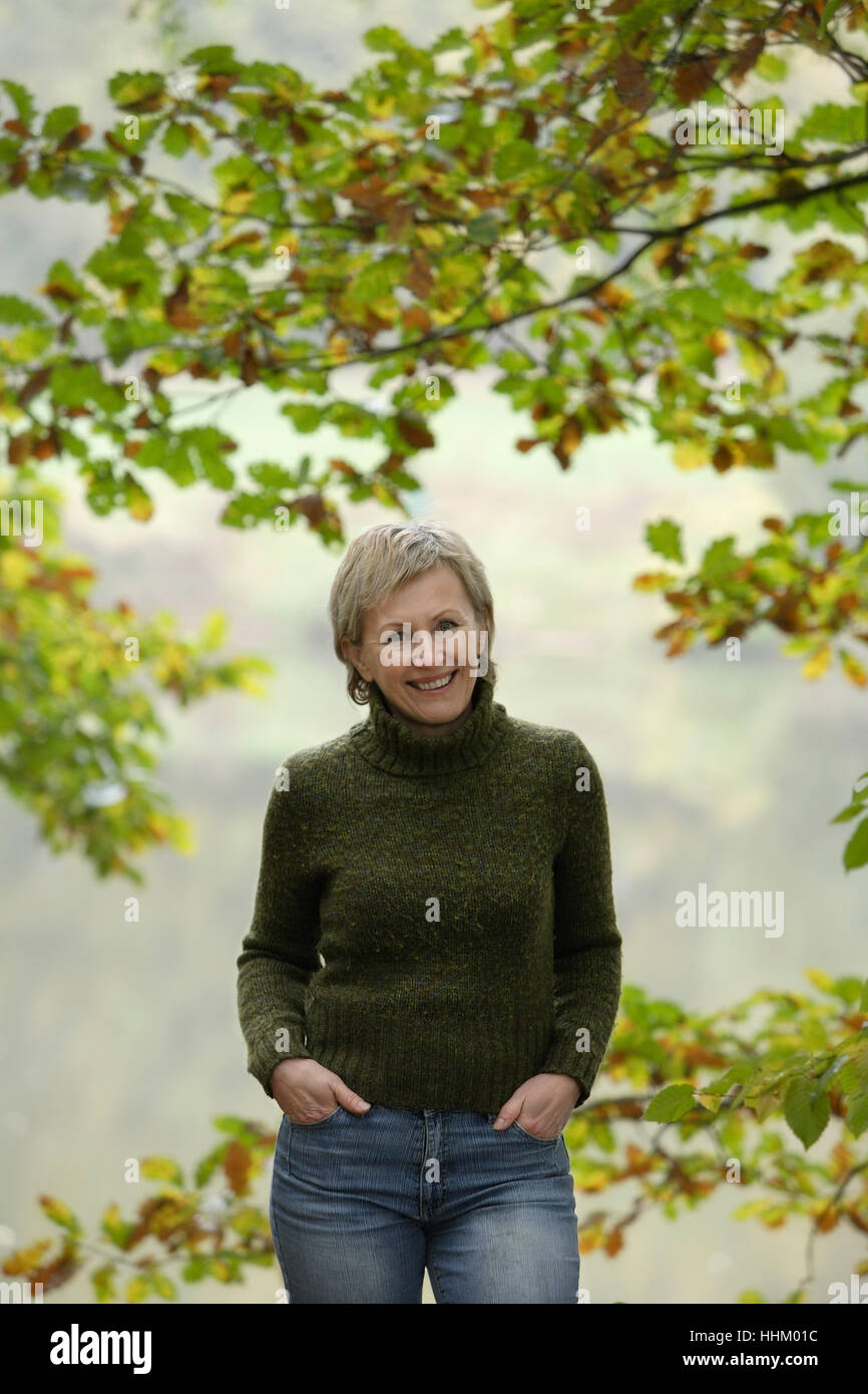 Senior woman standing under tree branches Stock Photo - Alamy