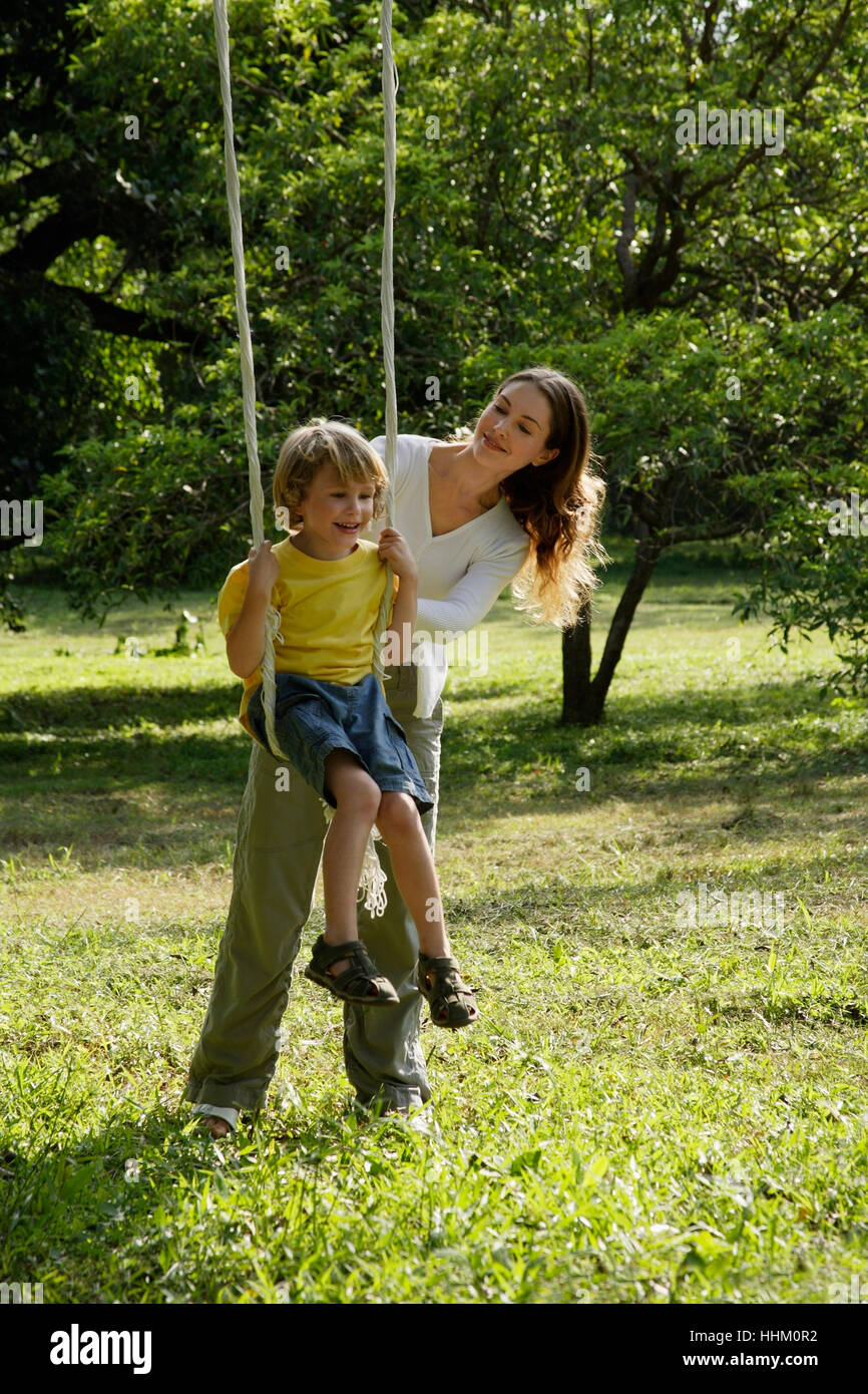 Mother pushing her son in a tree swing Stock Photo - Alamy