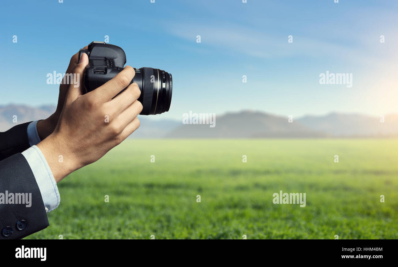 Close of man holding camera and taking photos of natural landscape ...