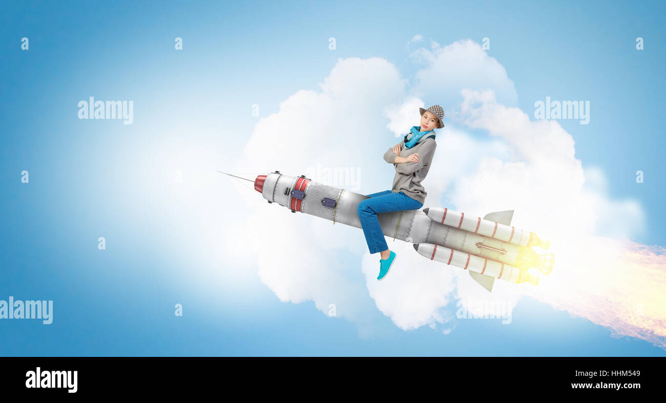 Young cheerful woman traveller riding rocket high in sky Stock Photo ...