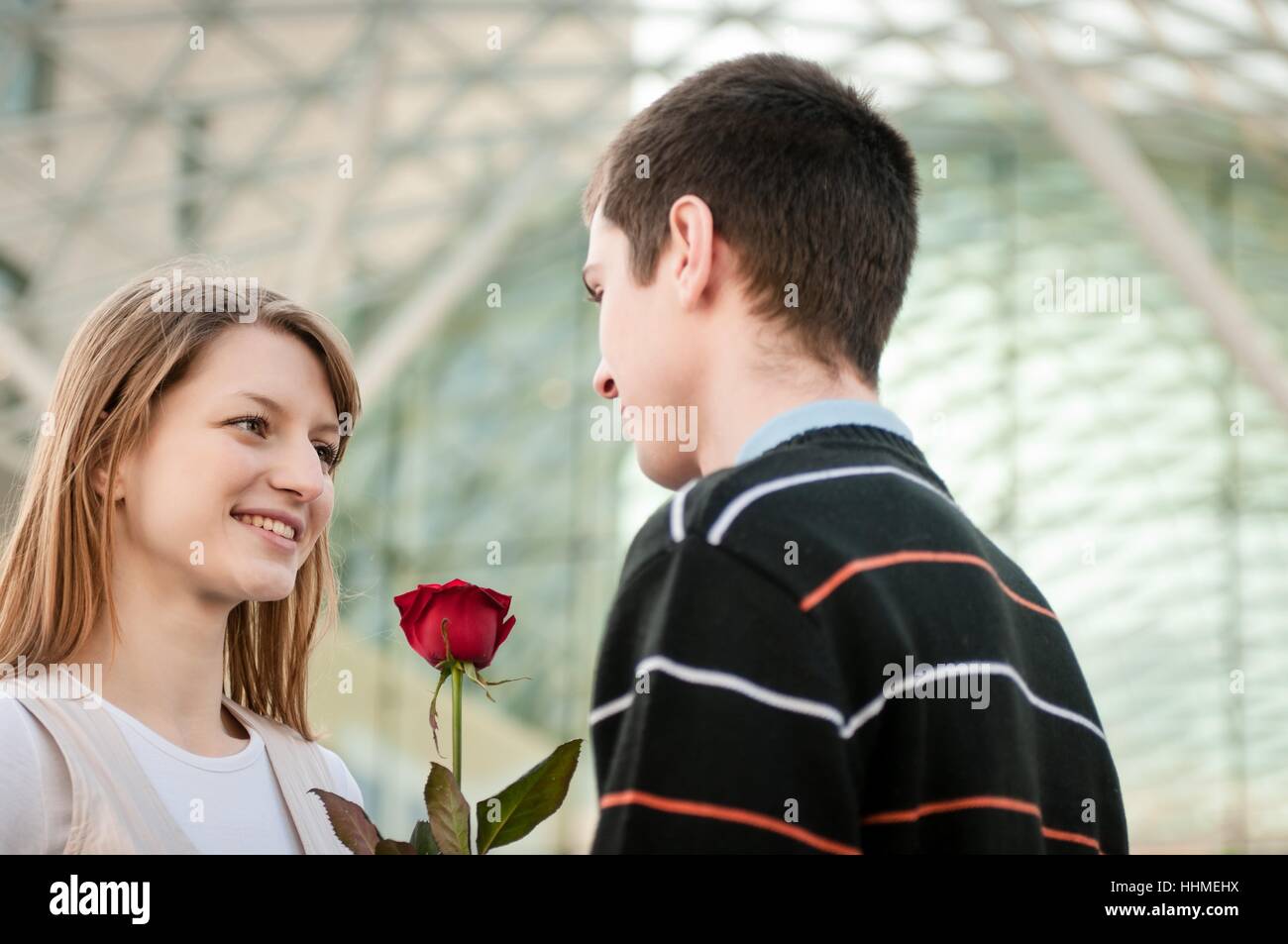 Young man handing over a flower (red rose) to woman - outdoor lifestyle ...