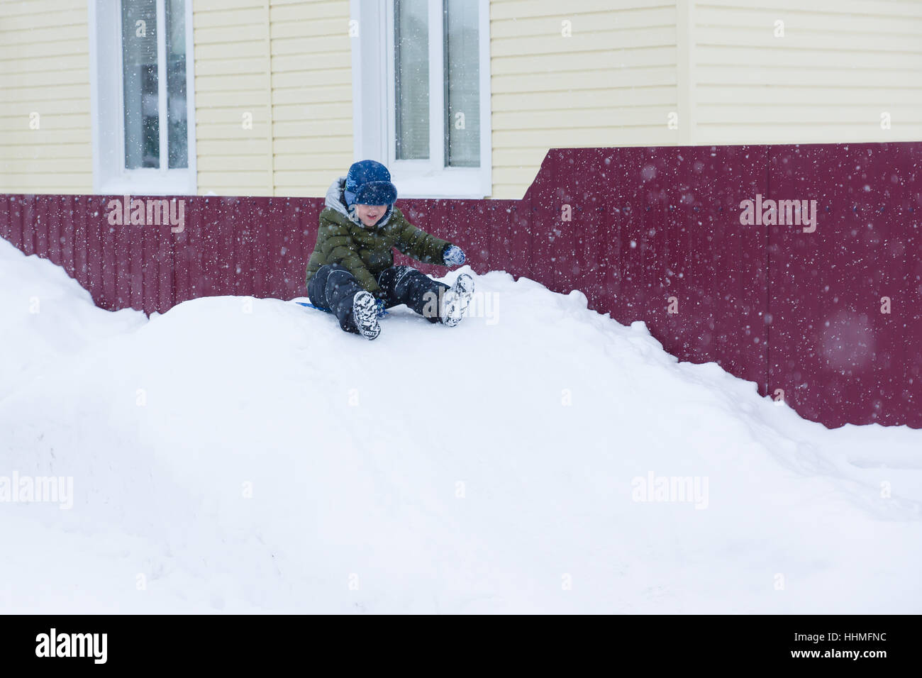 little boy in winter clothes sledding with snow slides Stock Photo - Alamy