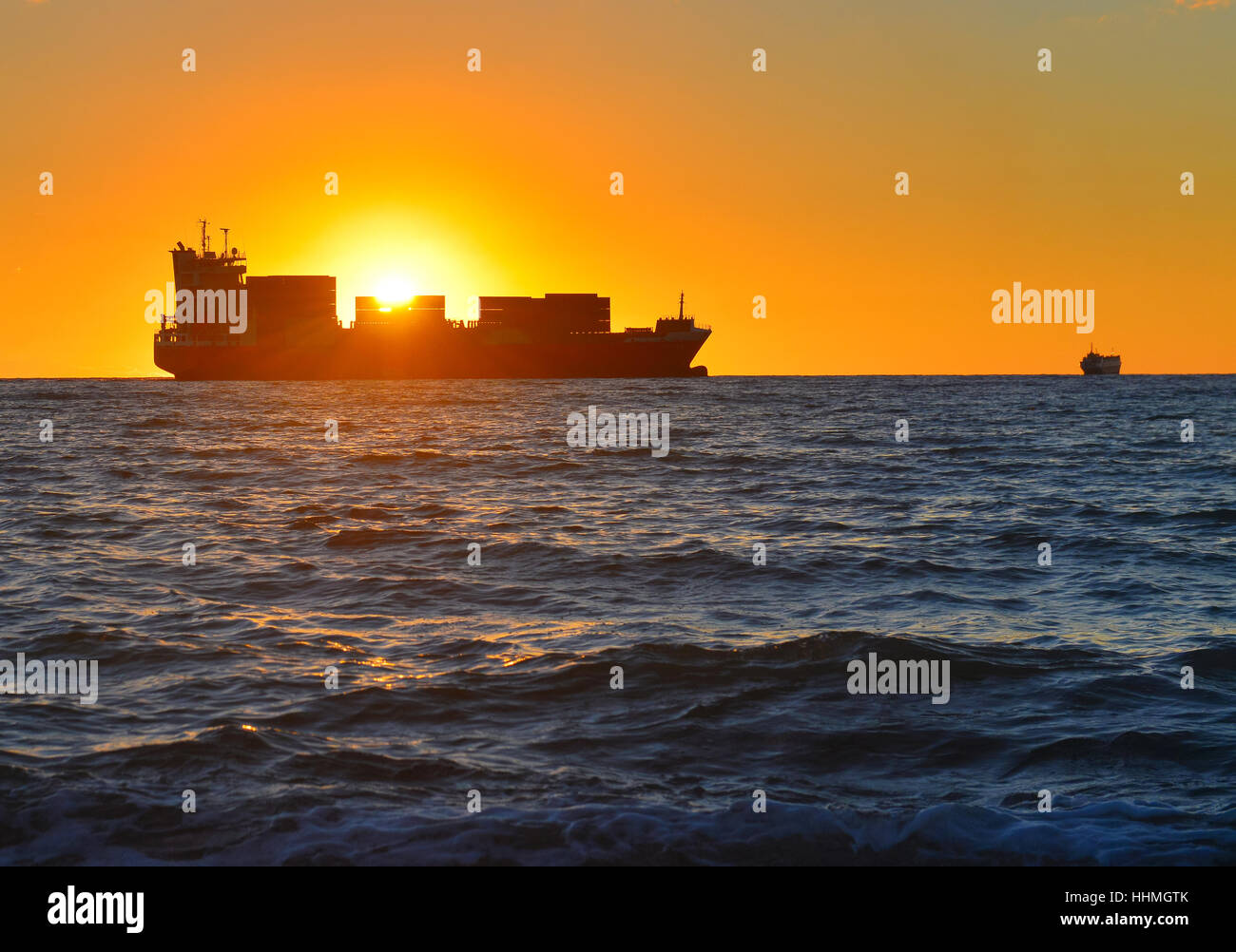 Seascape with cargo ship at sunset Stock Photo - Alamy