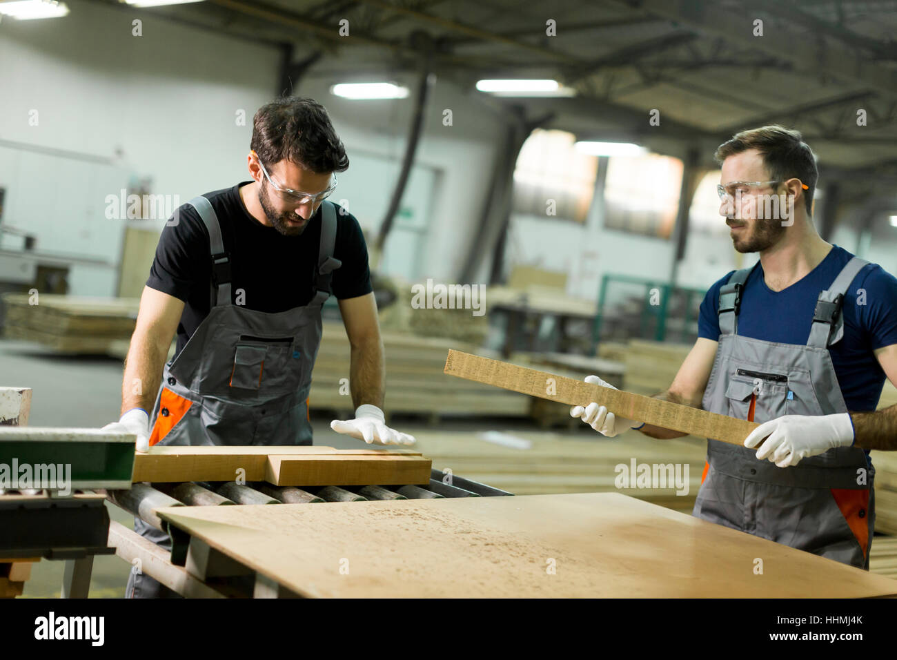 Two handsome young men working in lumber workshop Stock Photo - Alamy