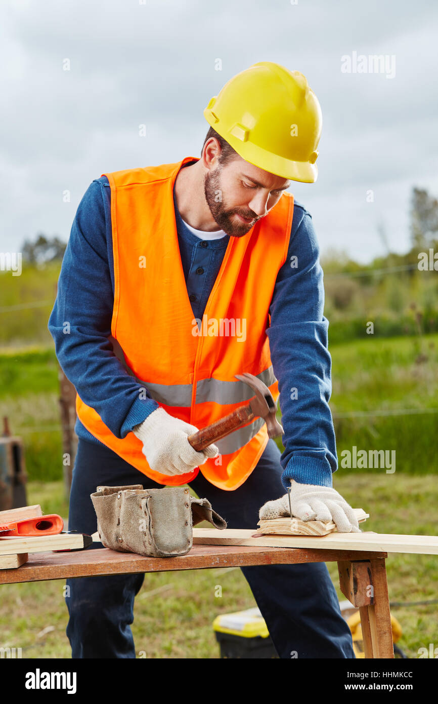 Carpenter hammering and working with wood at construction site Stock ...