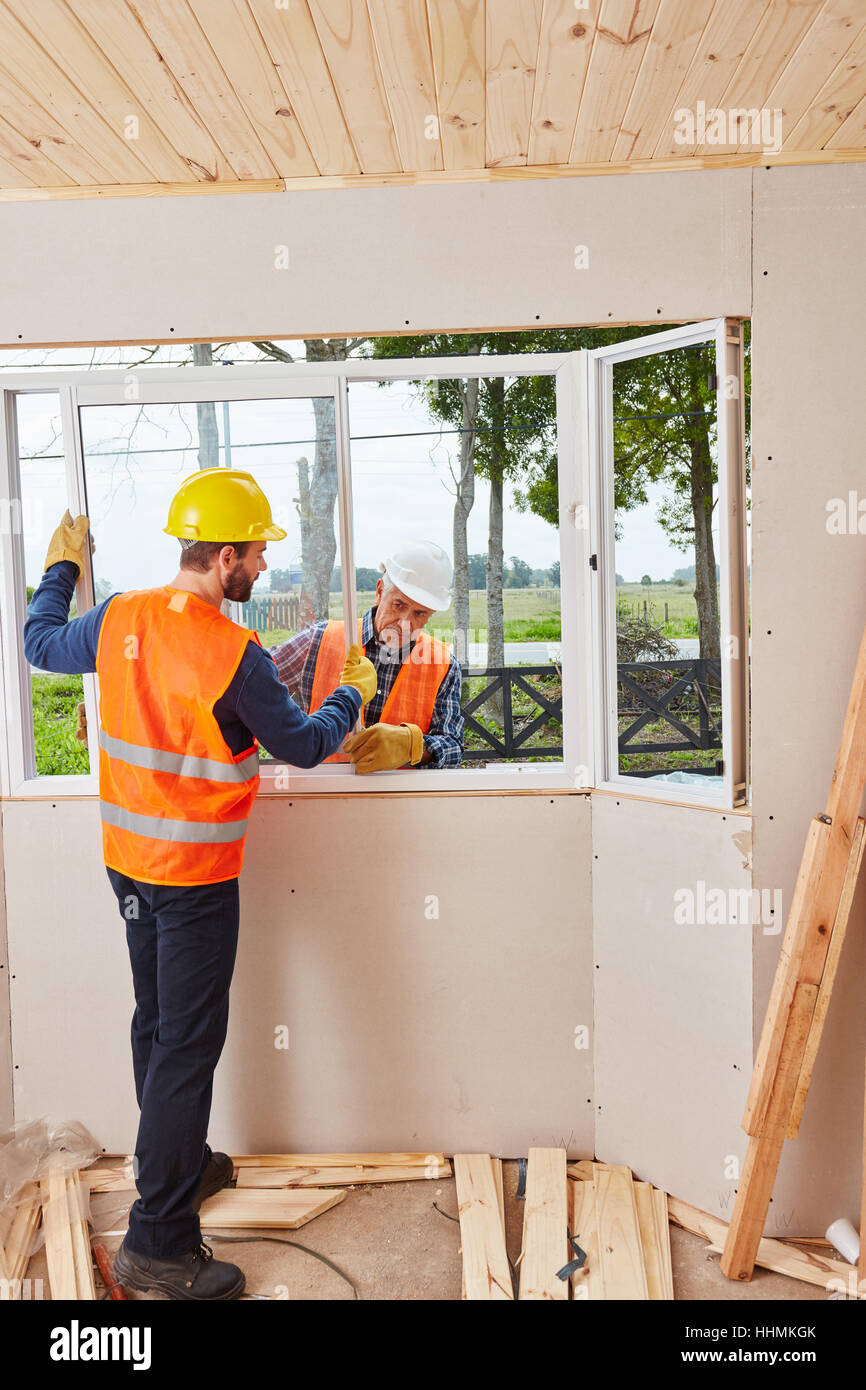 Skilled window fitters assembling window in teamwork Stock Photo - Alamy