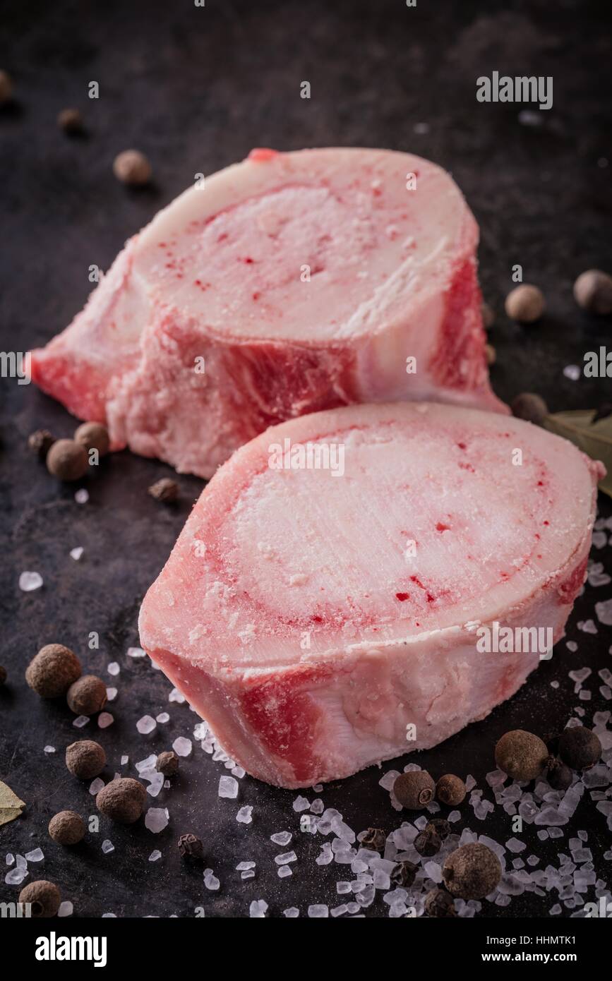 Vertical photo with two pieces or slices of big marrowbone with few ...