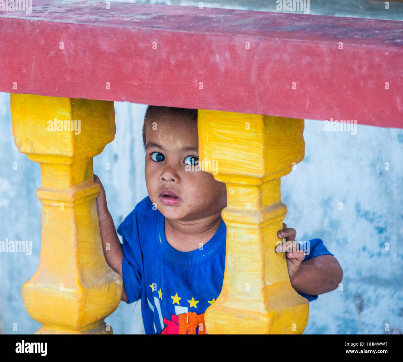 Little native boy looking through colourful balustrade, scared, Yangon ...