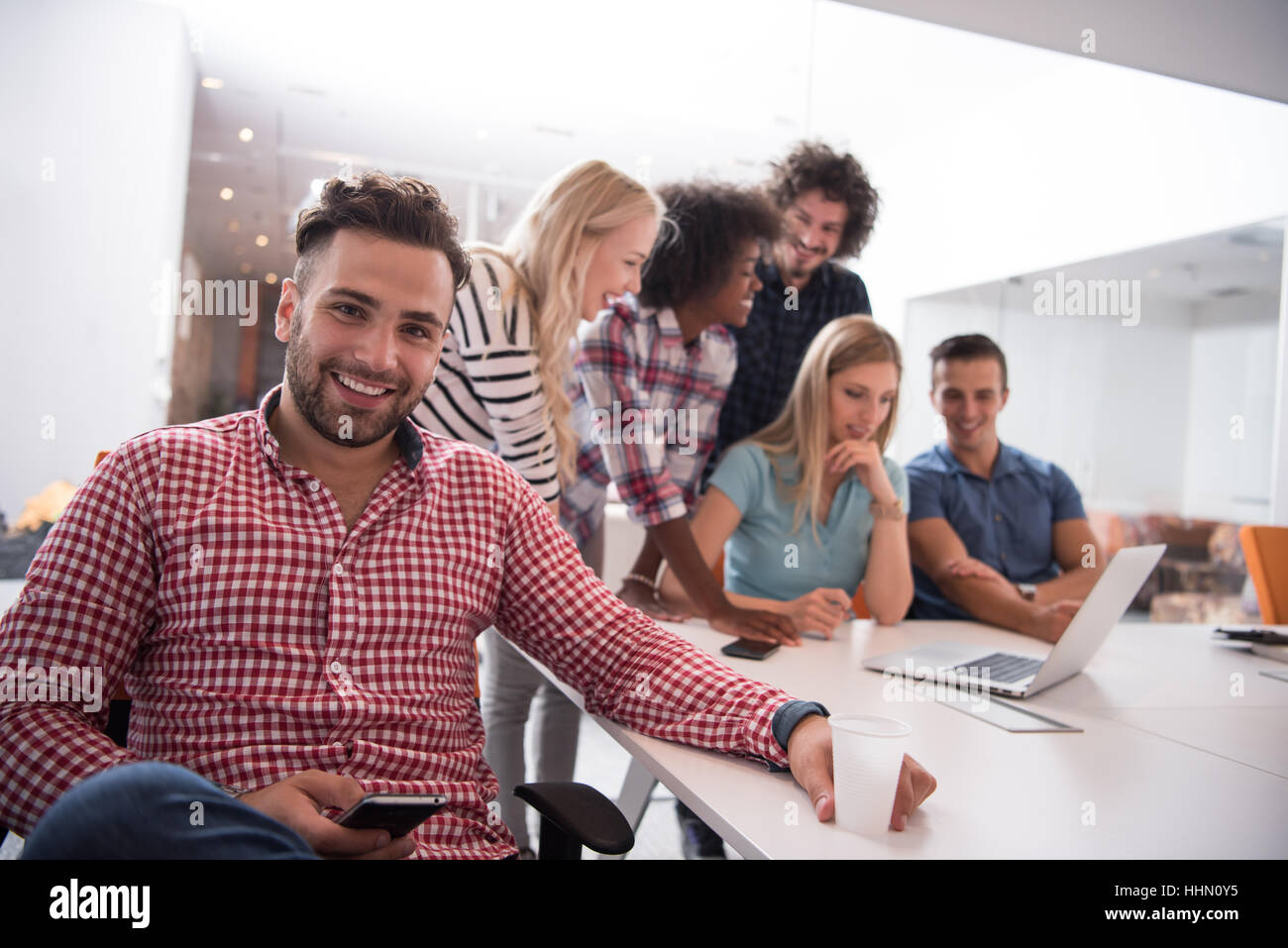 Portrait of smiling young informal businessman with colleagues in ...