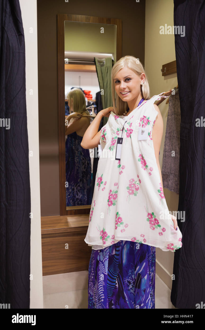 Woman standing on the changing room holding up dress Stock Photo - Alamy