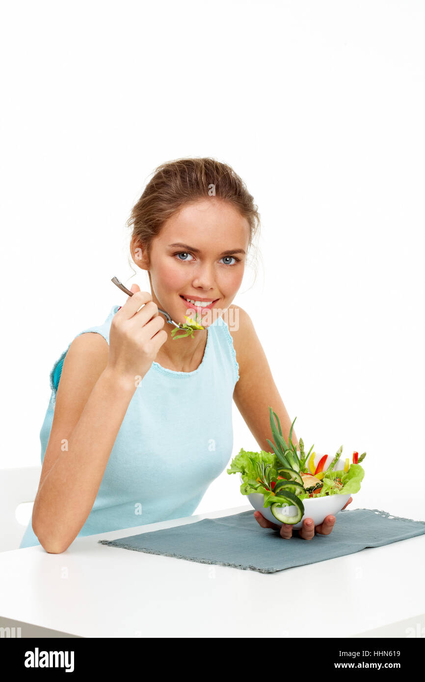 Portrait of pretty young girl with fork and bowl in hands eating ...