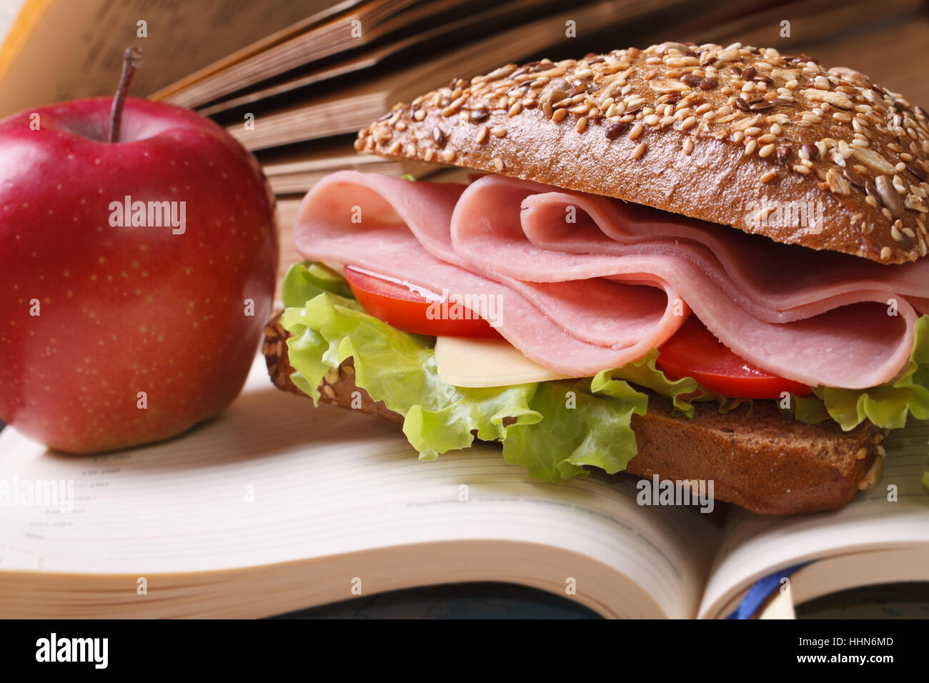 School lunch: a ham sandwich and an apple on open notebook close-up ...