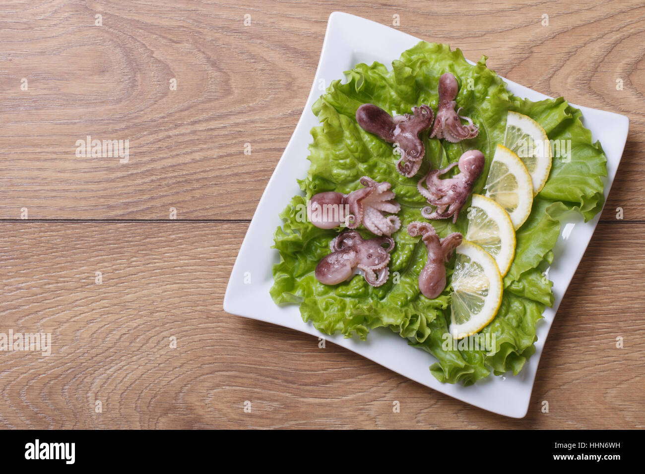 small octopus with lemon slices on lettuce leaves. view from above ...