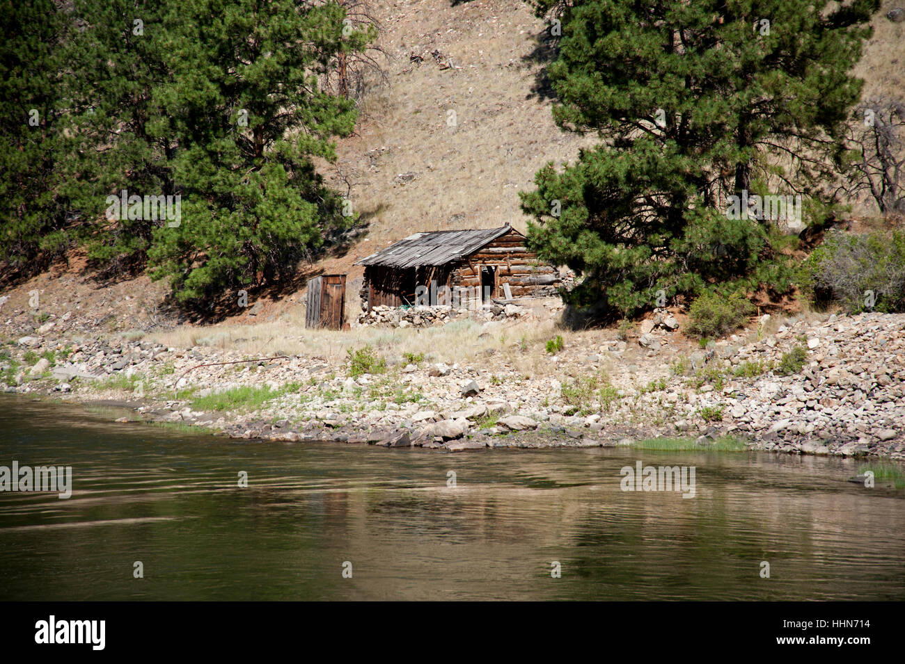 Abandoned cabin with outhouse, surrounded by trees, on the banks of the ...
