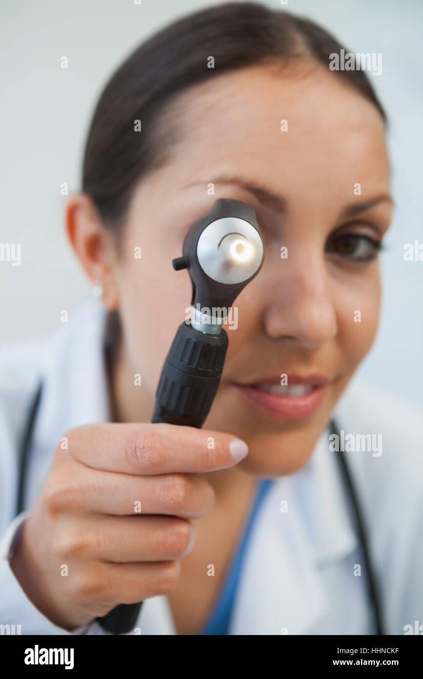 Doctor wearing lab coat looks through otoscope instrument Stock Photo ...