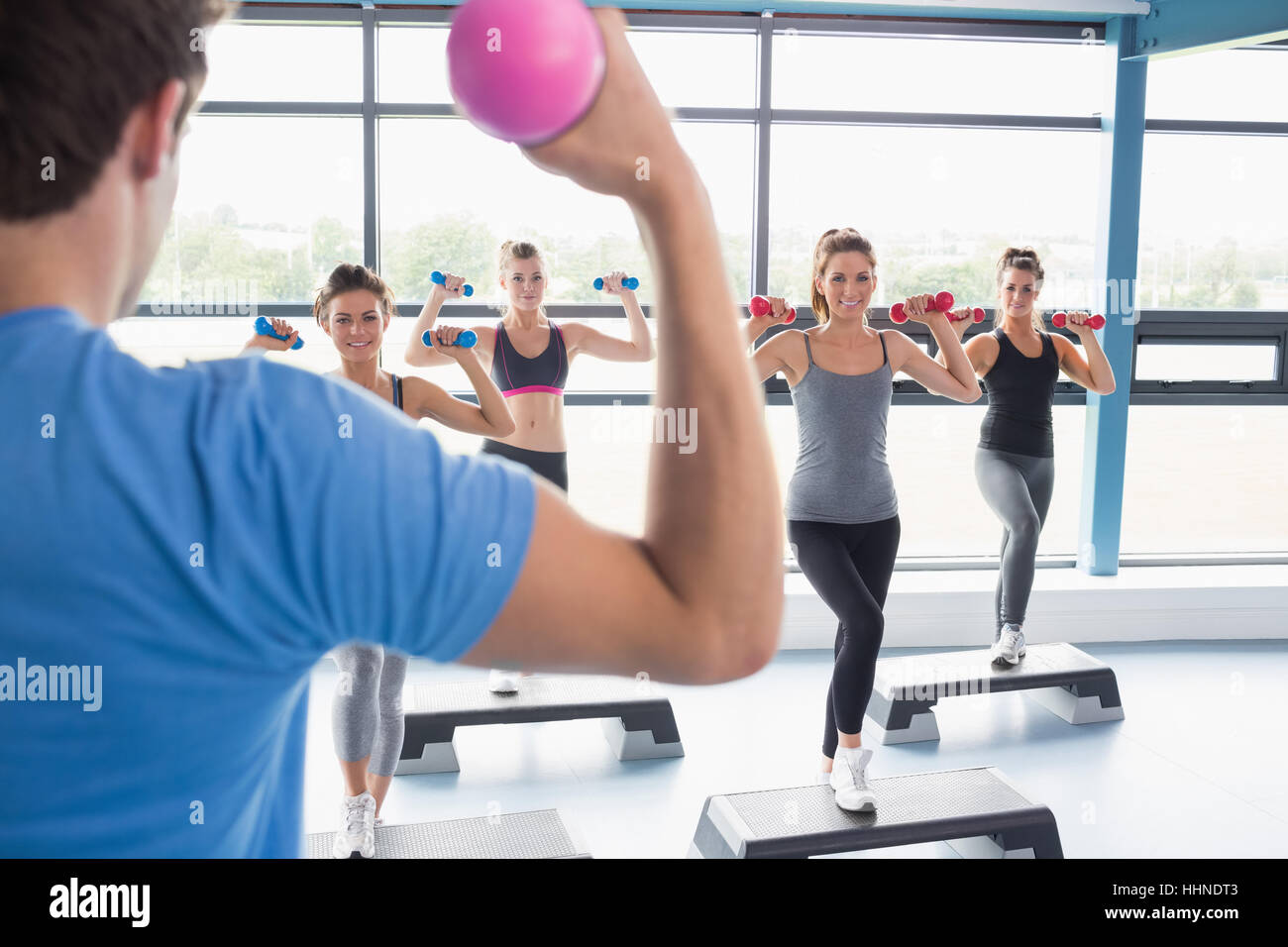 Trainer teaching his aerobics class while lifting weights in gym Stock ...