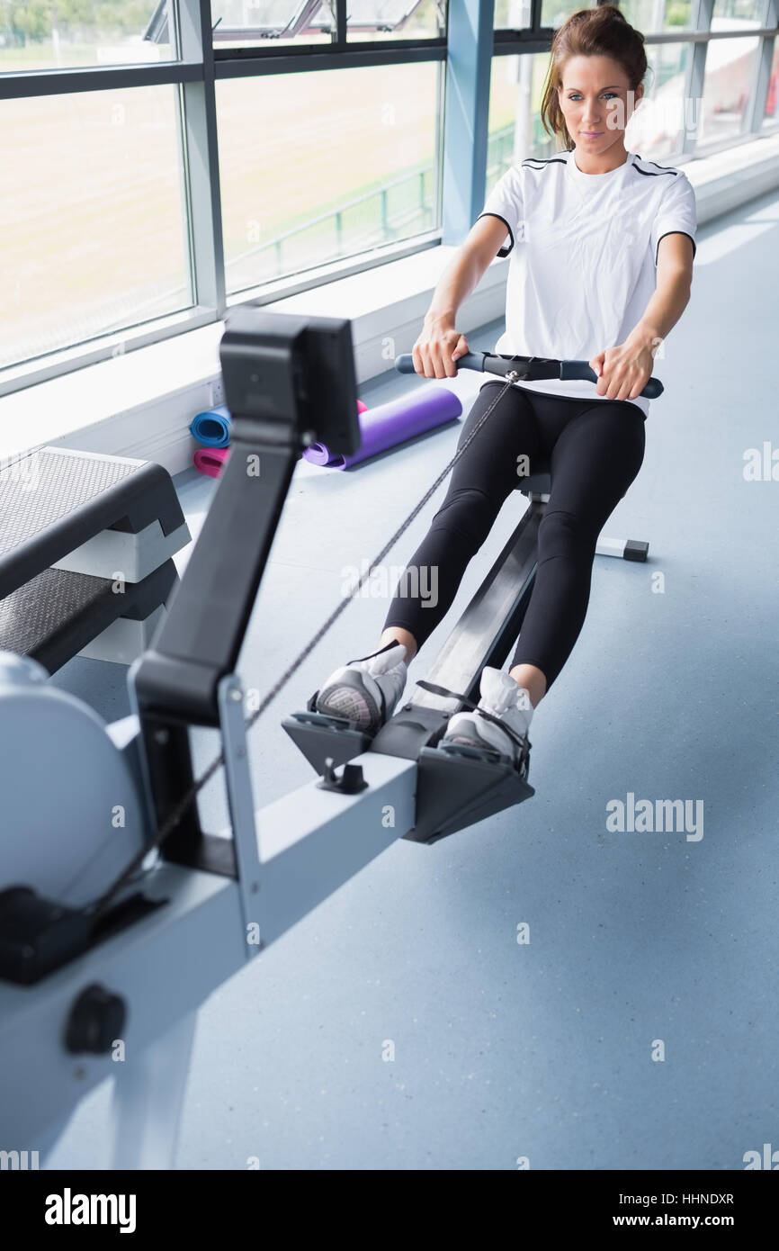 Energetic woman training on row machine in gym Stock Photo - Alamy