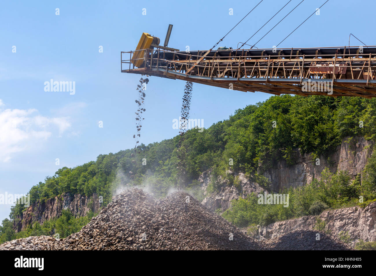 A conveyor belt transports crushed rock in a rock quarry into large ...