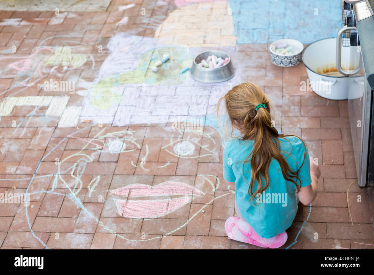 Caucasian girl drawing face with chalk on patio bricks Stock Photo - Alamy
