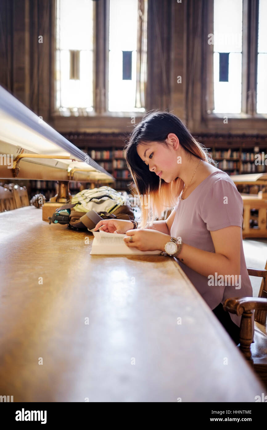 Chinese woman sitting in library reading book Stock Photo - Alamy