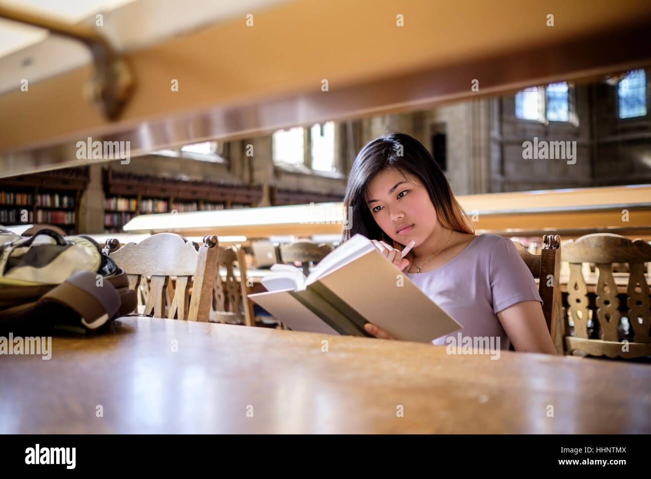 Chinese woman sitting in library reading book Stock Photo - Alamy