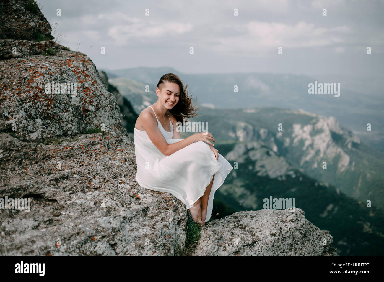Smiling Caucasian woman sitting on rock overlooking landscape Stock ...