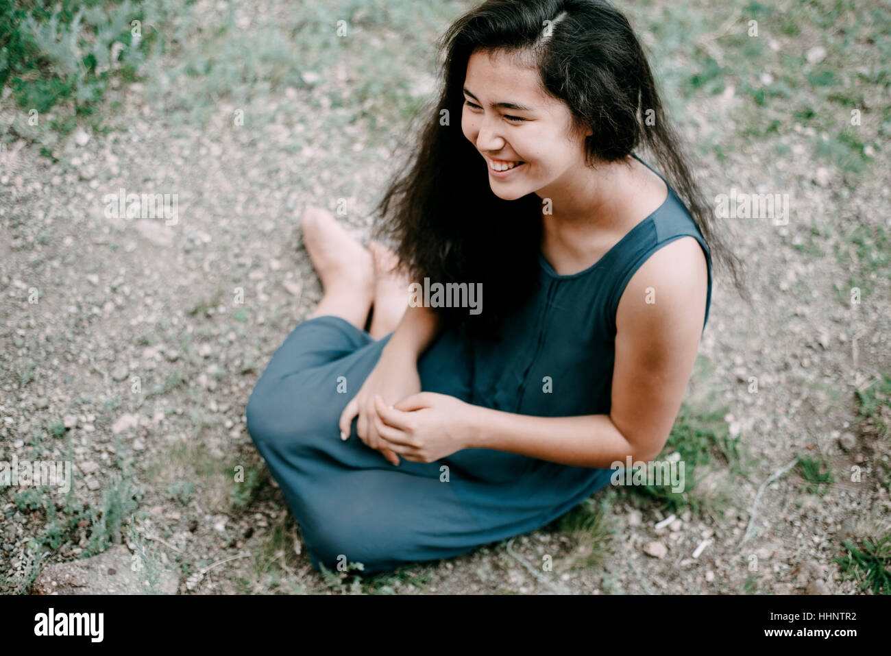 Smiling Asian woman sitting on ground Stock Photo - Alamy
