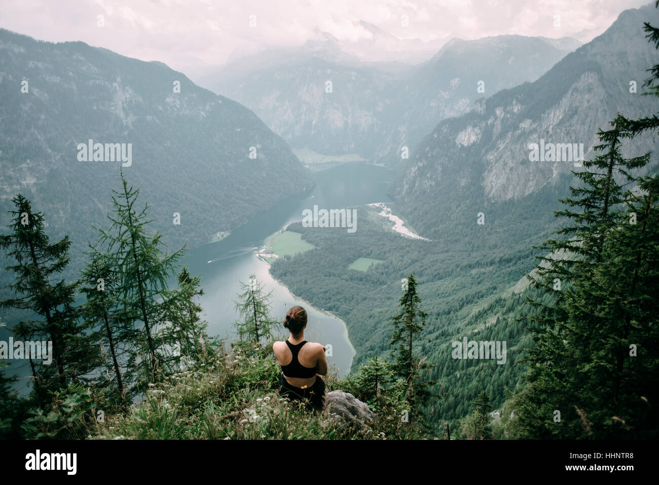 Caucasian woman sitting on rock overlooking lake in valley Stock Photo ...