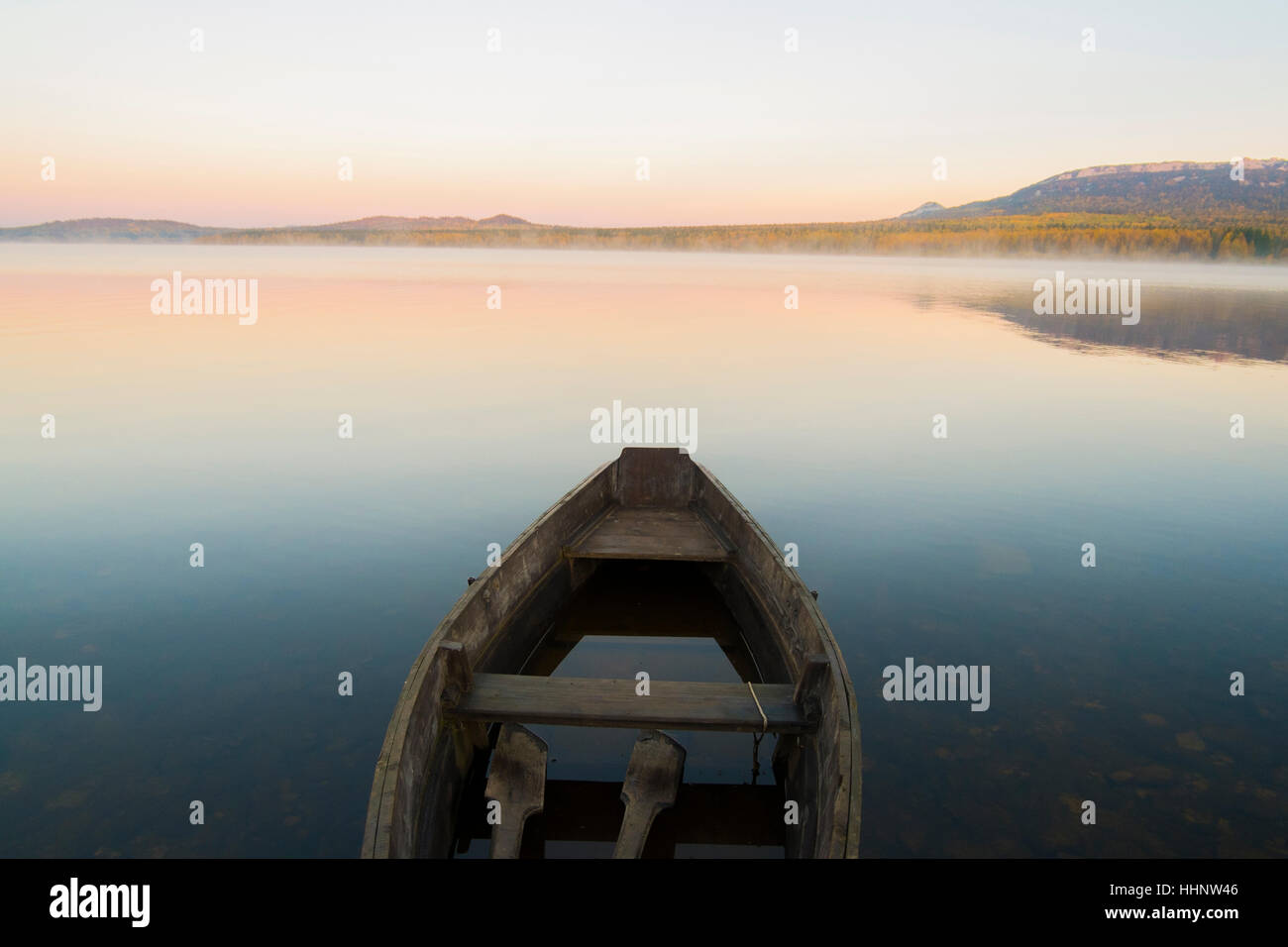 Empty rowboat on lake at sunset Stock Photo - Alamy