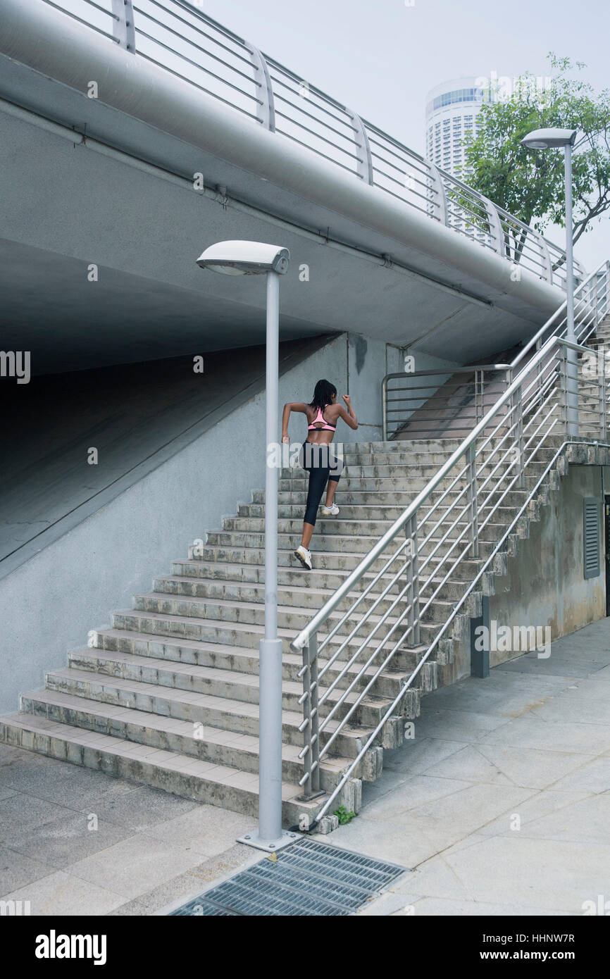 Mixed Race woman running up urban staircase Stock Photo - Alamy