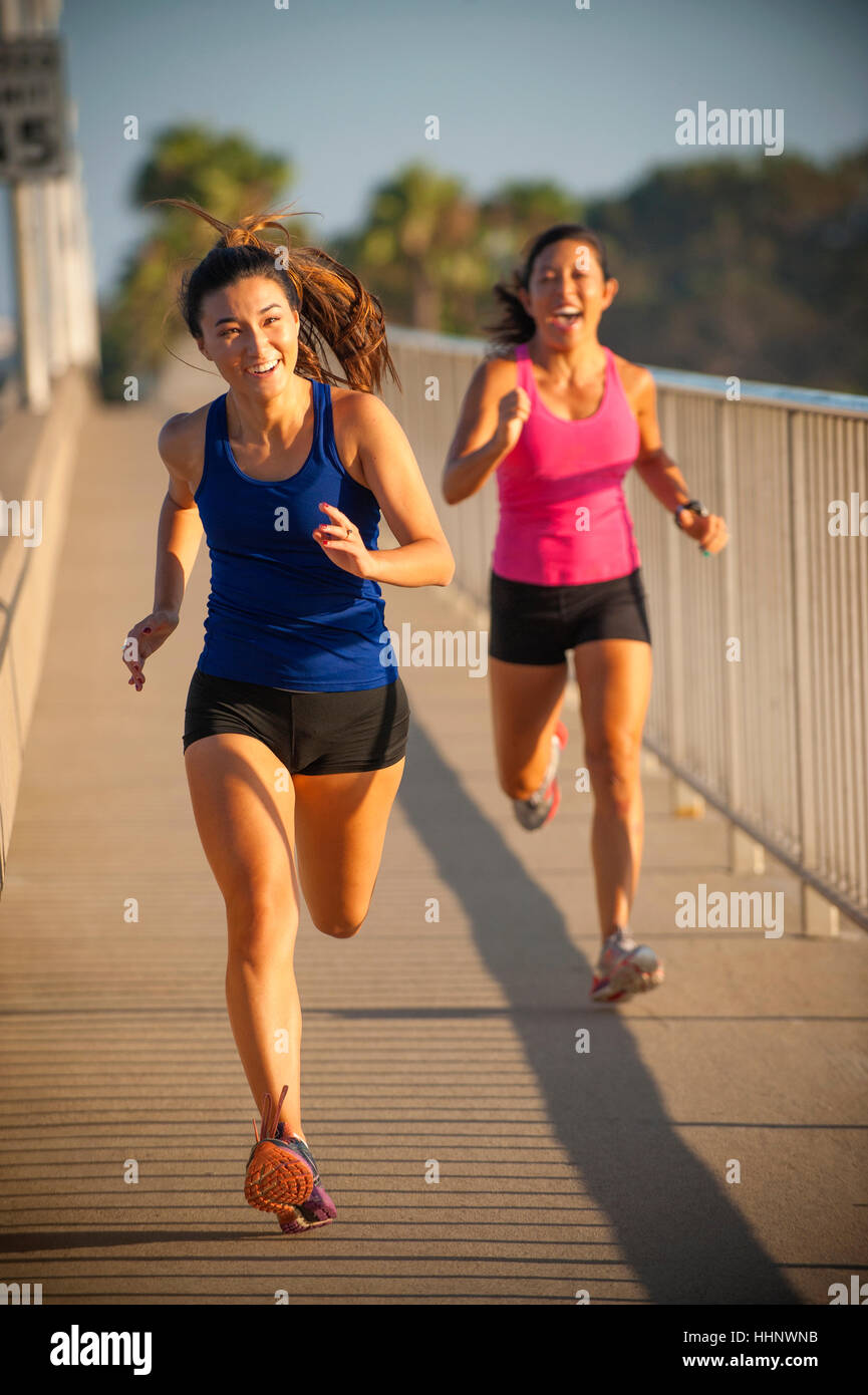 Mixed Race mother and daughter running near railing Stock Photo - Alamy