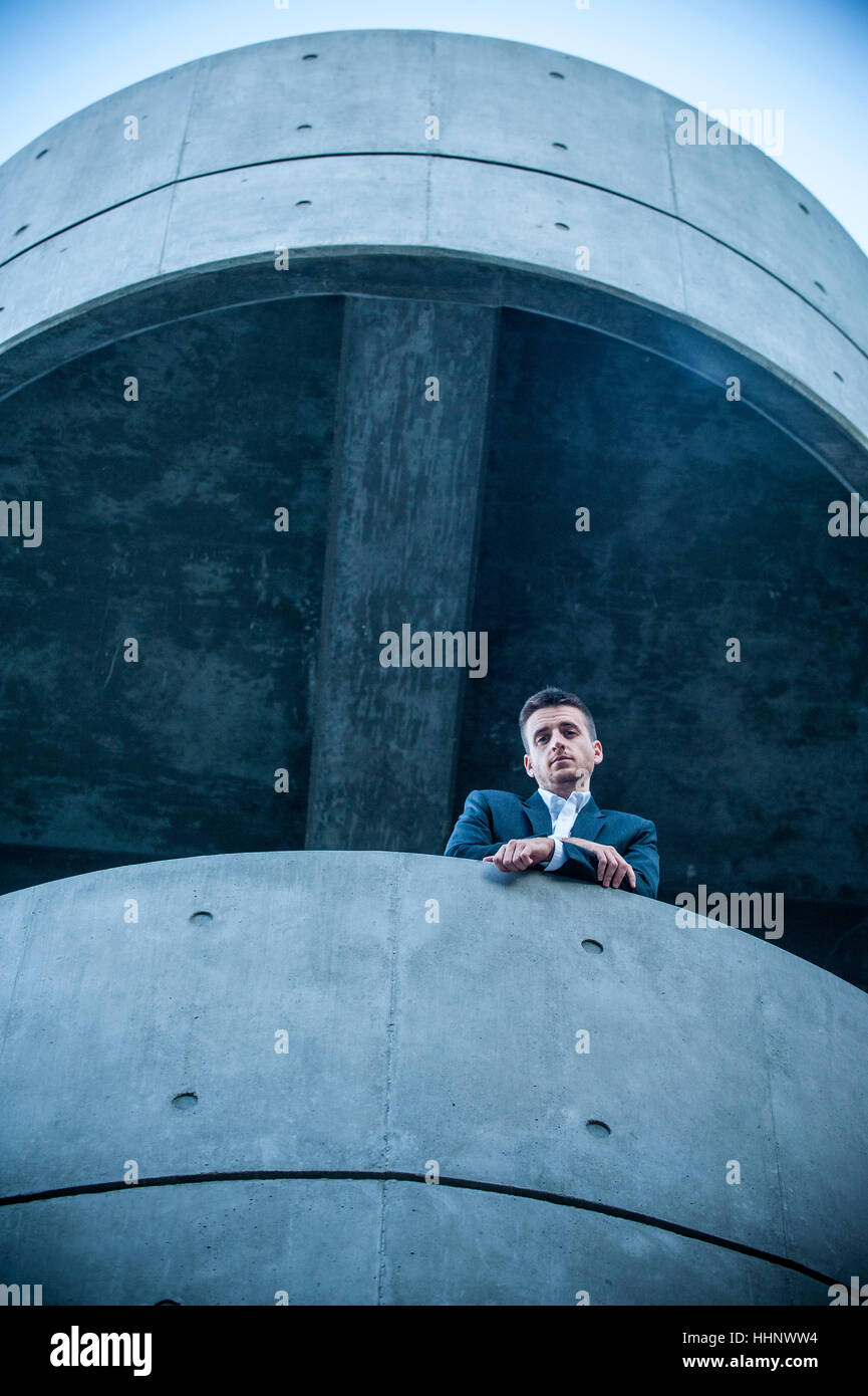 Low angle view of businessman leaning on balcony Stock Photo - Alamy