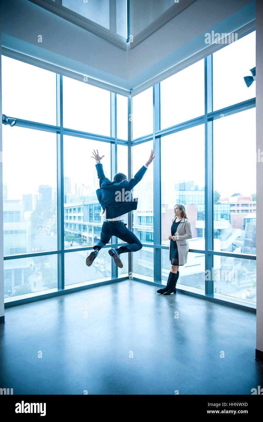 Businesswoman watching businessman celebrating near window Stock Photo ...