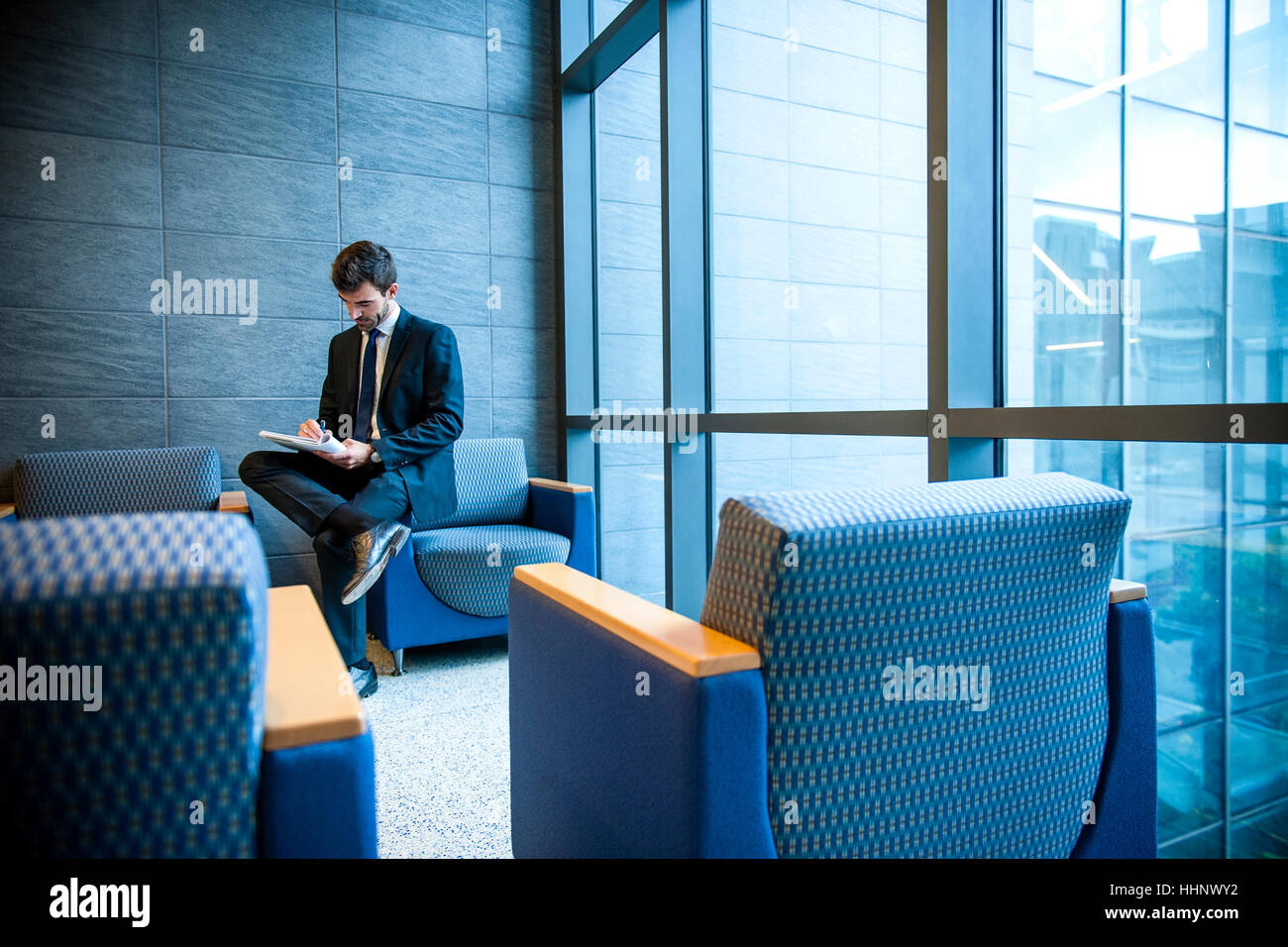 Hispanic businessman writing on notepad in office lounge Stock Photo ...
