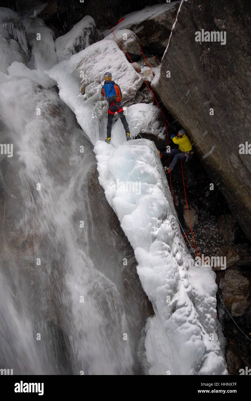 Photographer suspended from fixed climbing ropes on edge of partially ...