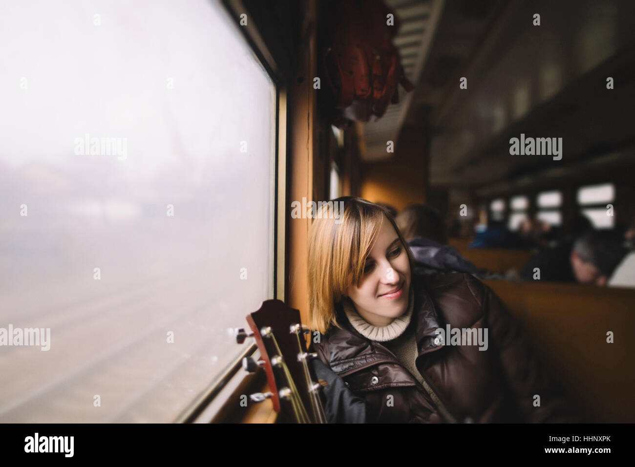 Smiling Caucasian woman with guitar sitting near window on train Stock ...