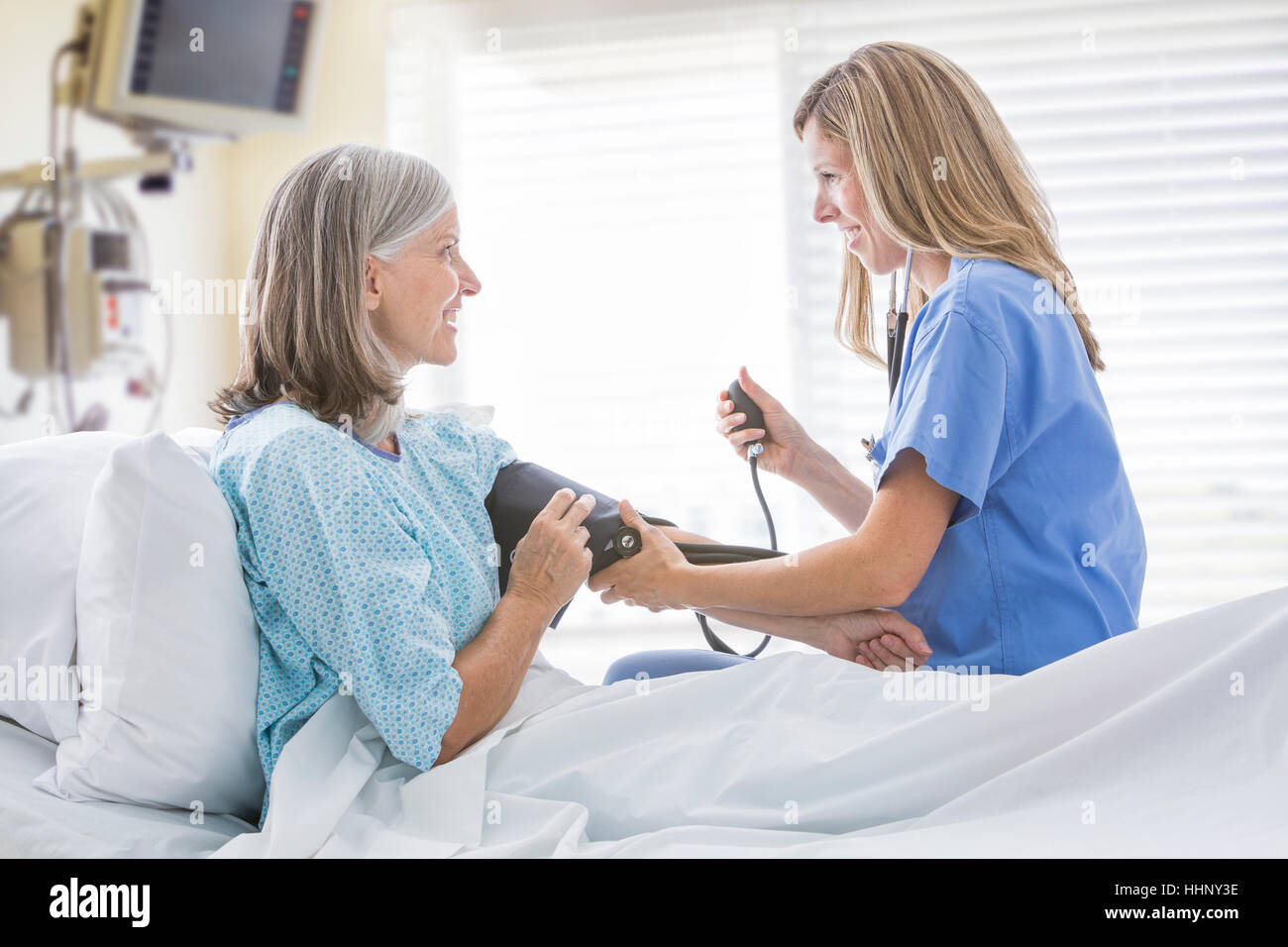 Caucasian nurse measuring blood pressure of woman in hospital bed Stock ...