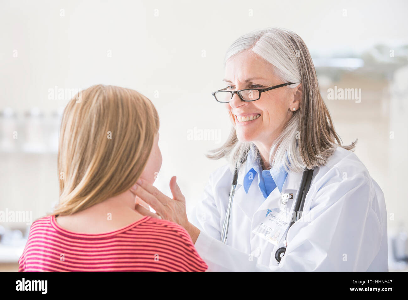 Caucasian doctor checking neck of girl Stock Photo - Alamy