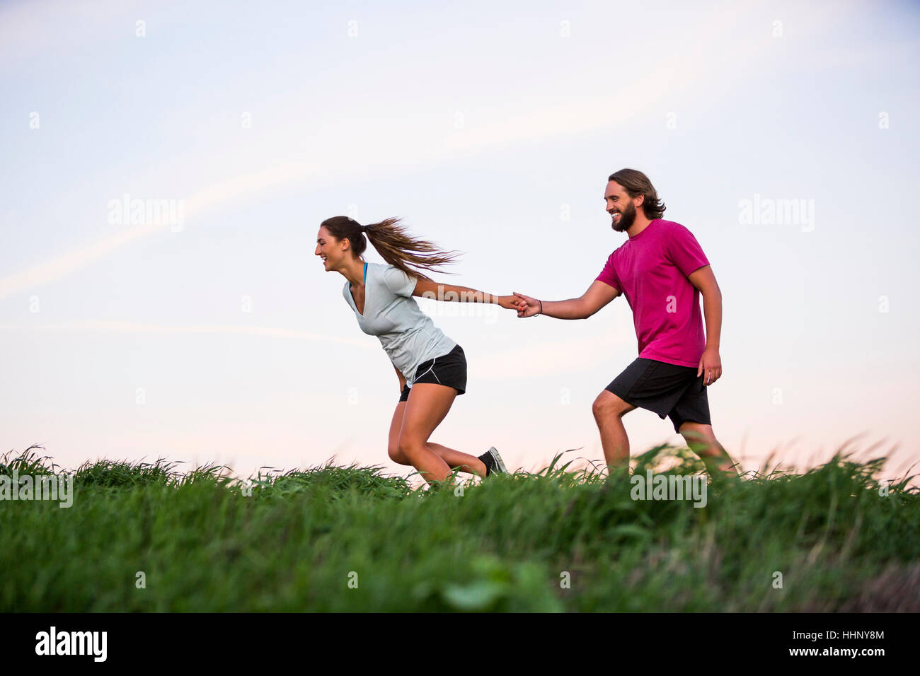 Caucasian woman pulling man on hill Stock Photo - Alamy