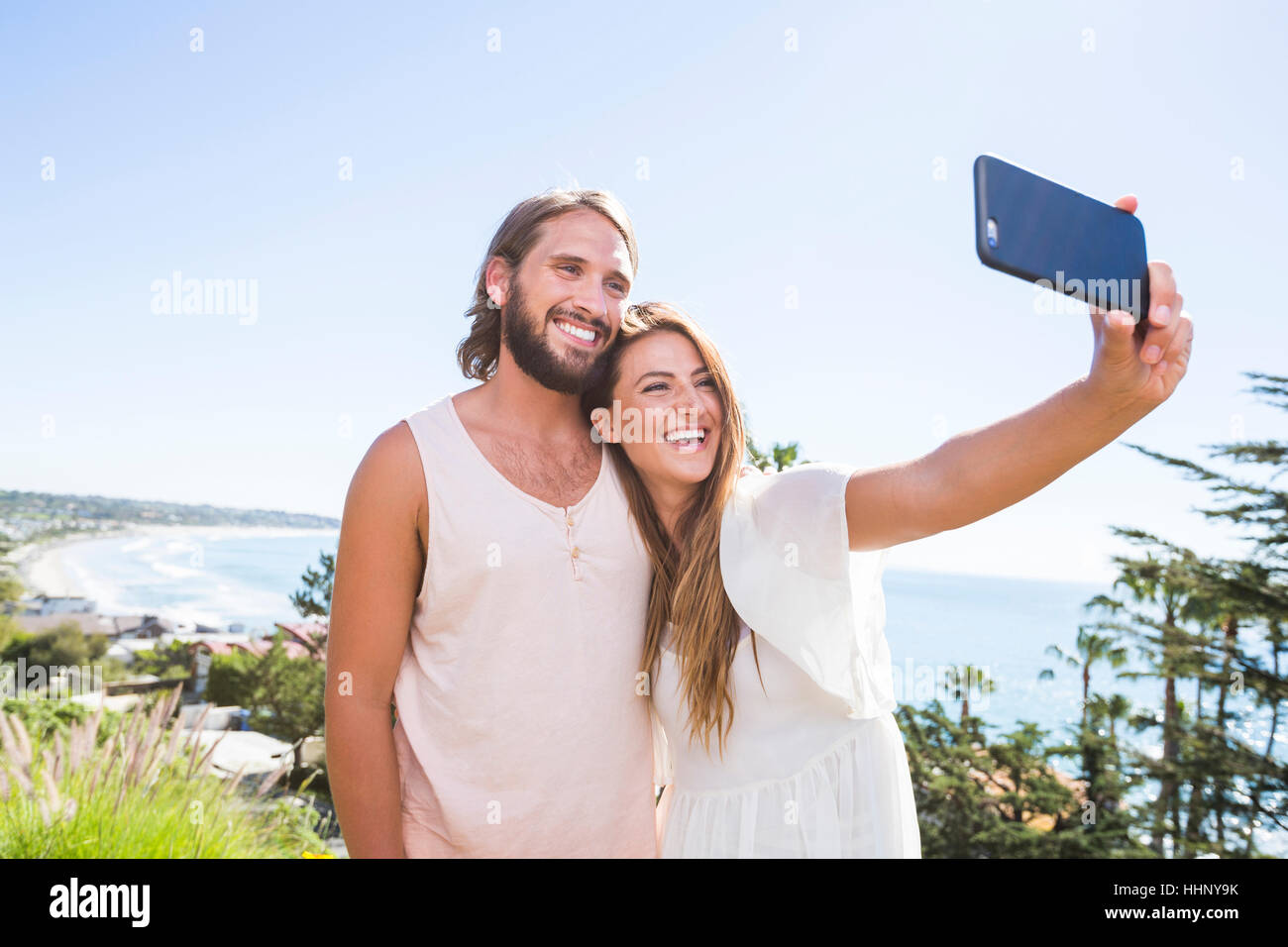 Caucasian couple posing for cell phone selfie at beach Stock Photo - Alamy