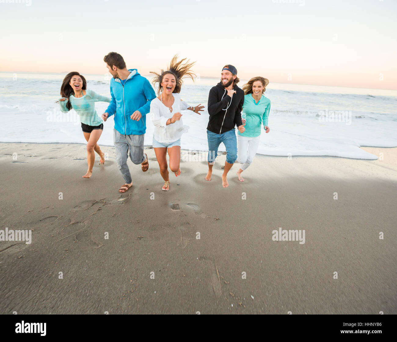 Smiling friends running on beach Stock Photo - Alamy